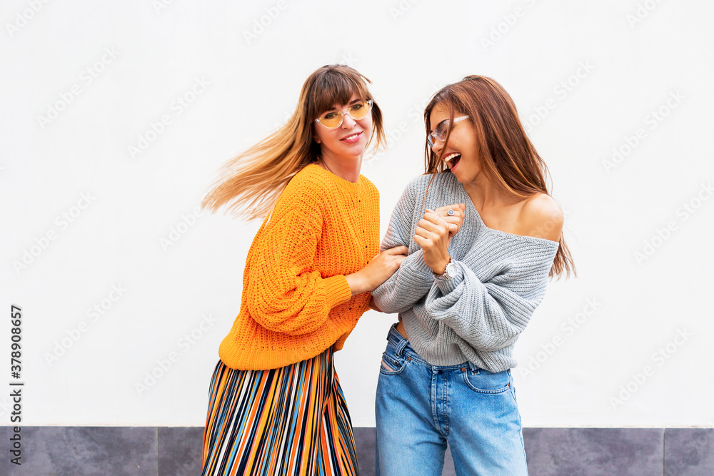 Two positive girls standing back to back on white background ...