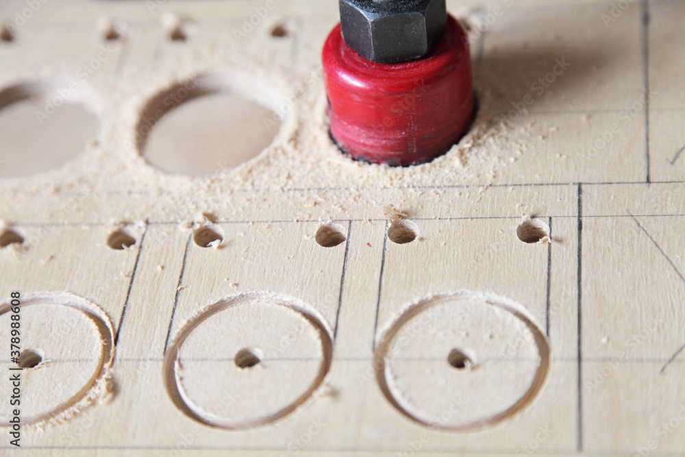 Plywood with markings and a drill with a circular crown drill bit ...