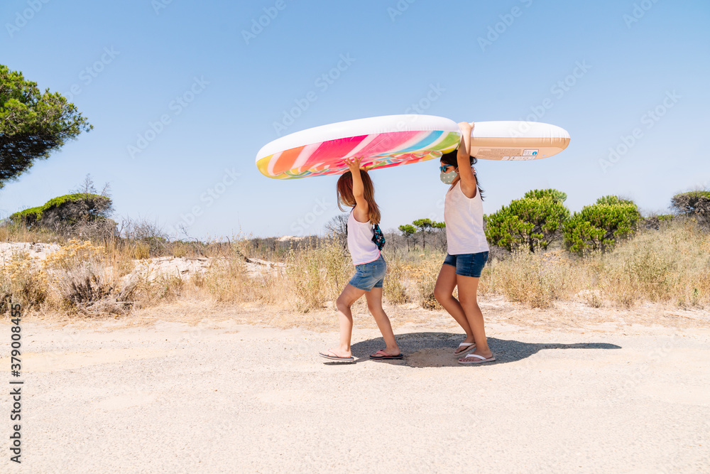 two girls with a mask on their face and glasses walking around a pine ...