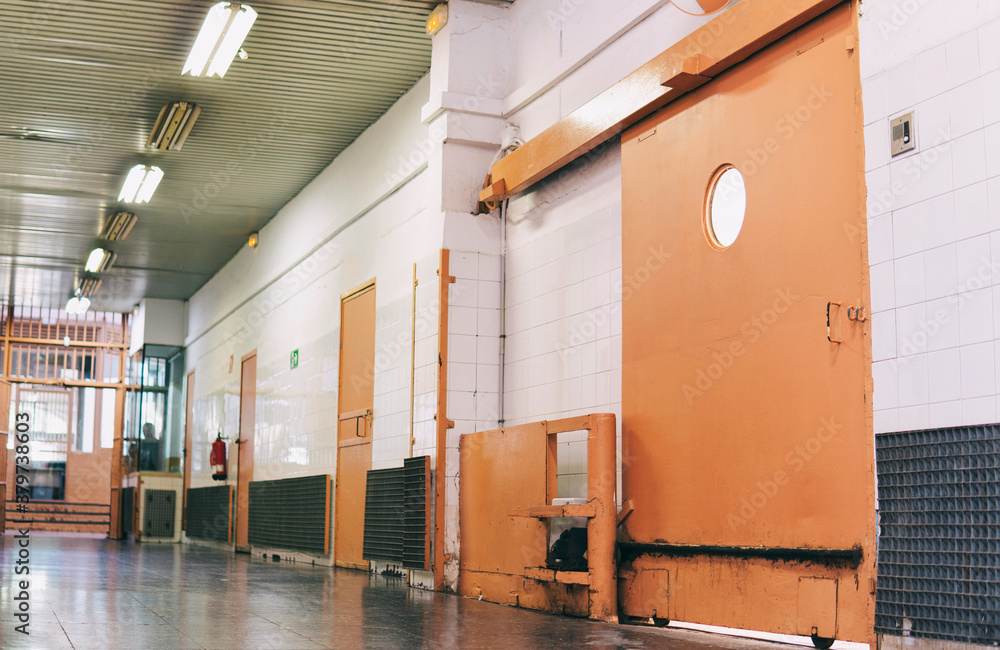 Old prison corridor or aisle with automatic sliding metal gates or ...