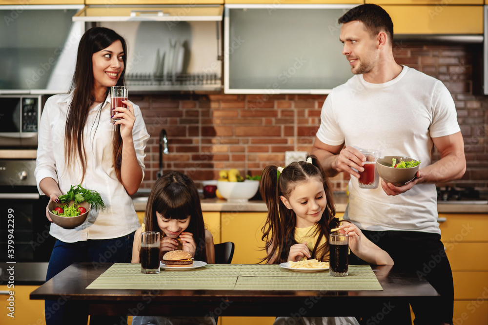 Healthy eating vs bad habits. Parents offer their daughters a salad ...