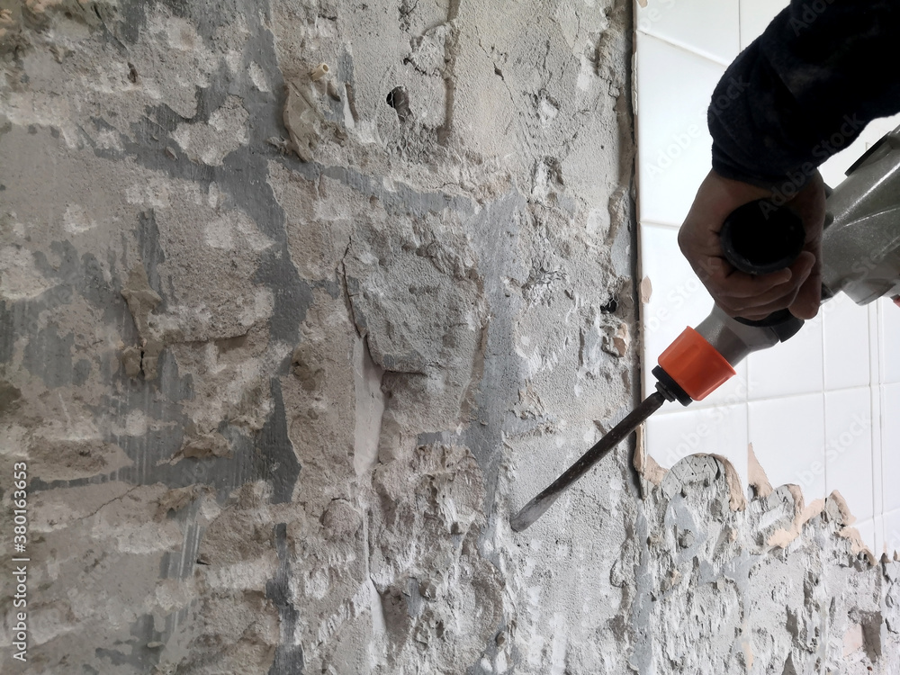Construction worker using a handheld demolition of old tiles with ...