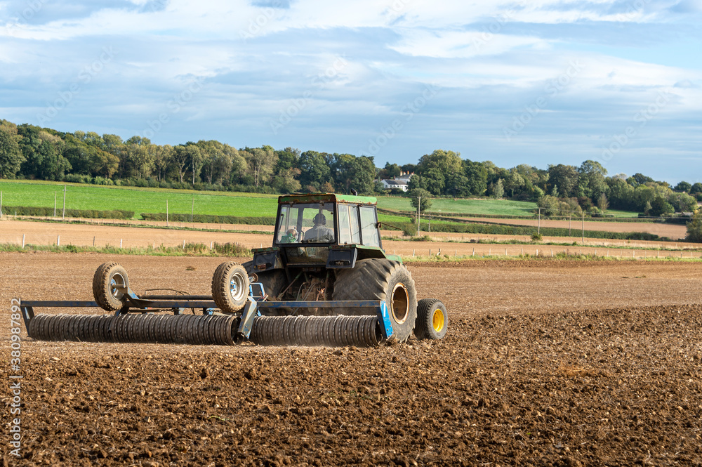 Tractor cultivating field at spring Stock Photo | Adobe Stock