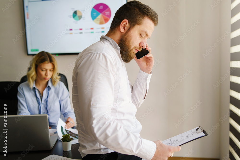 Young director at work with secretary making a phone call while holding ...