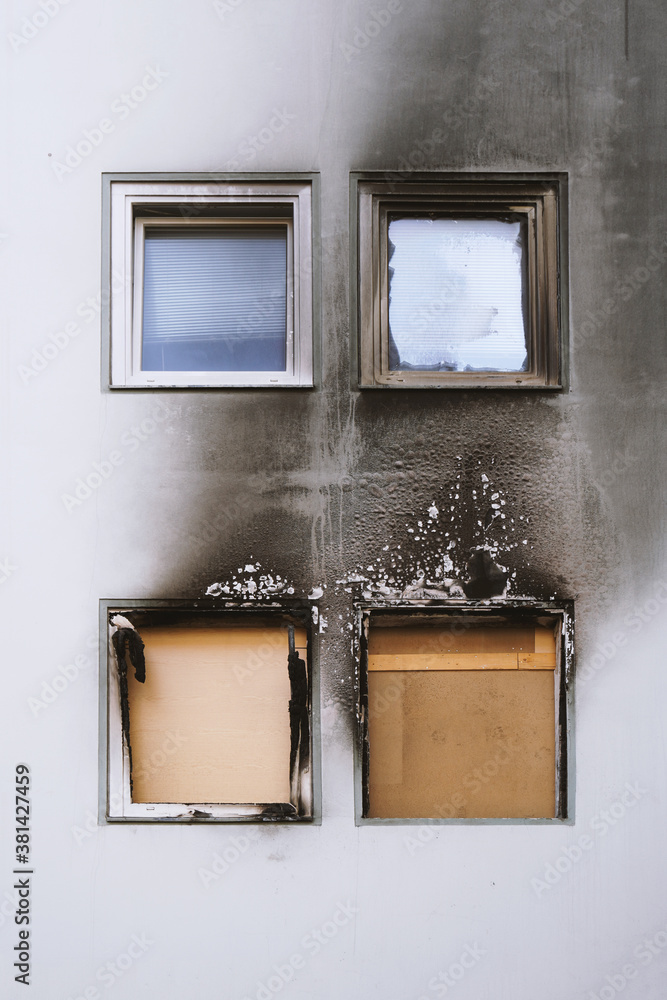 house or home fire - boarded up windows and burned facade blackened by ...