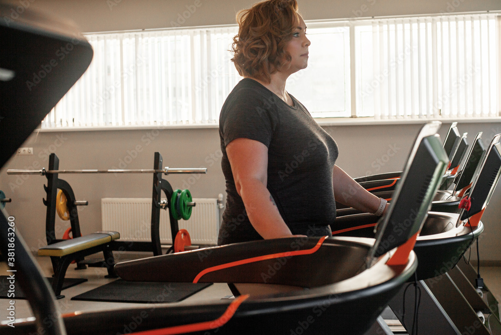 Fat woman fights overweight in the gym, doing heavy fitness exercises ...