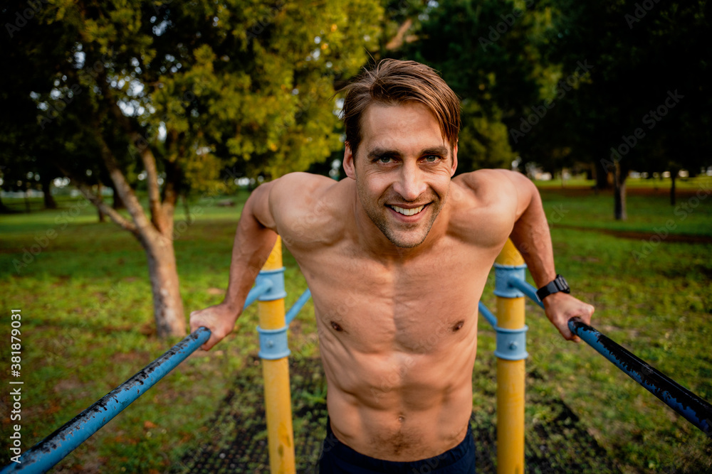 Smiling attractive young male athlete building arm muscle strength ...