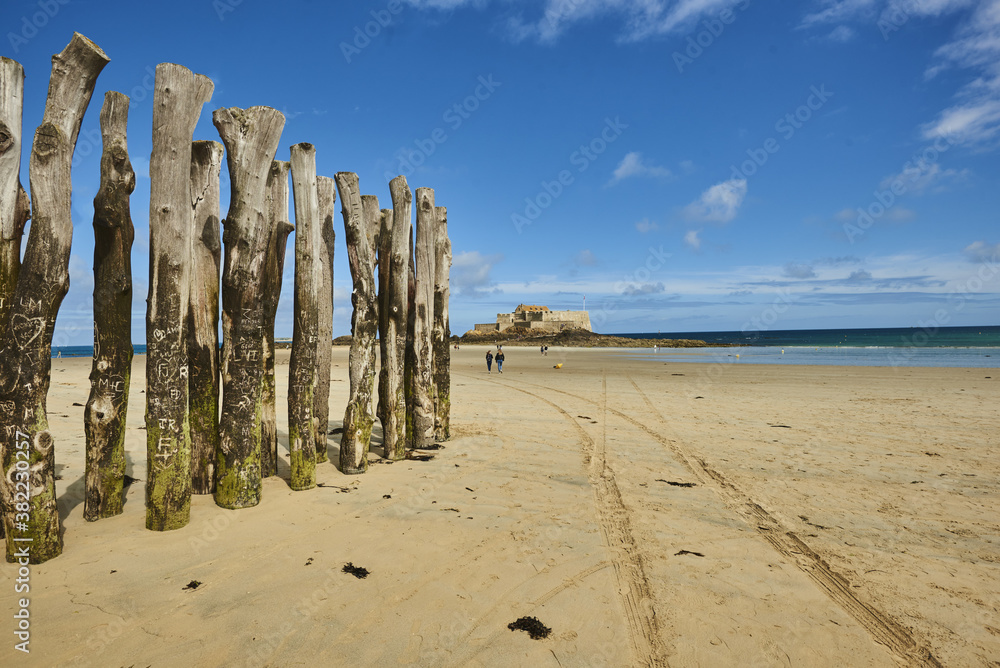 Wooden Poles et Fort National on the beach at low tide in Saint Malo ...