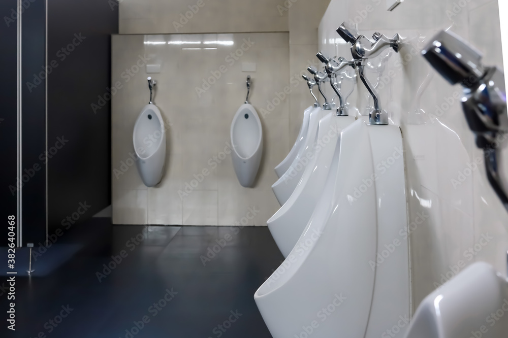 White urinal contrasts with black space in men's bathrooms Side view ...