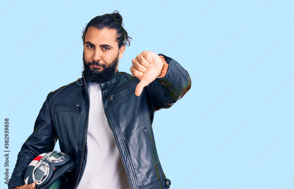 Young arab man holding motorcycle helmet with angry face, negative sign ...