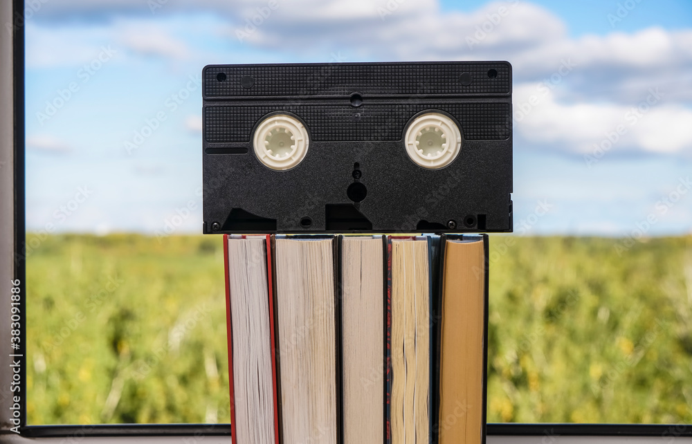 VHS cassette on stack of books. blue sky background. Window frame ...