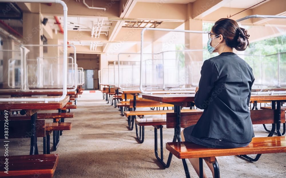 Woman sitting behind a plastic partition (or table shield) setting on ...