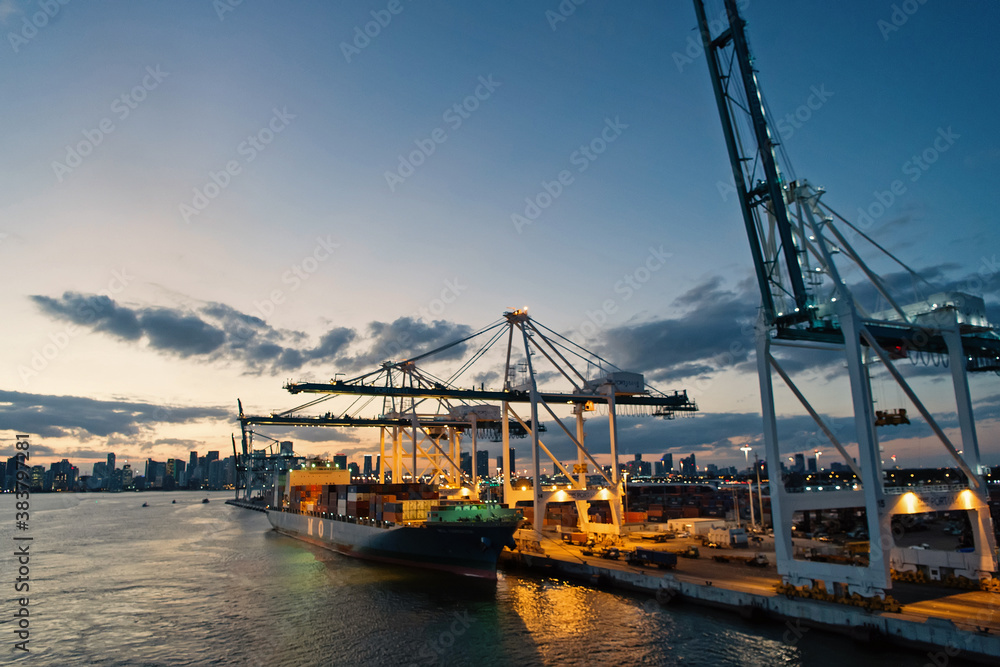 cargo ship and cranes in sea port on evening sky. Maritime container ...