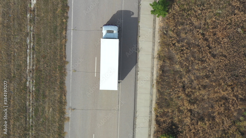 Aerial view of truck with trailer driving on straight road and ...