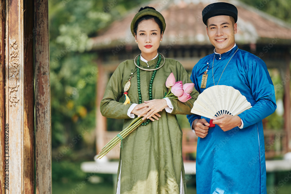 Young Vietnamese couple in national costumes standing with lotus ...