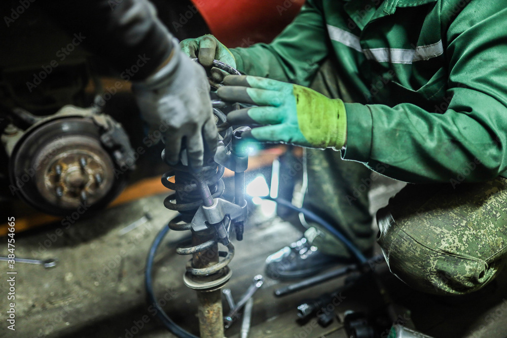 Auto mechanics compress the spring with zip ties to replace the shock ...