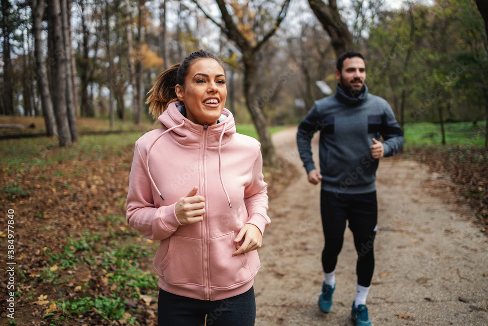 Smiling fit woman running fast in front of her friend. They are ...