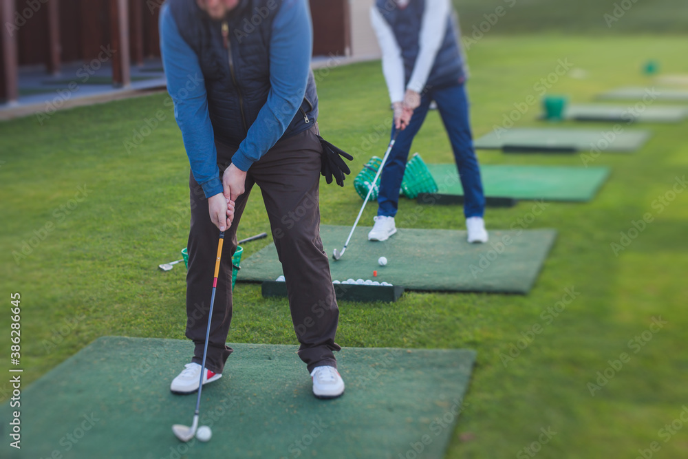 Group of golfers practicing and training golf swing on driving range ...