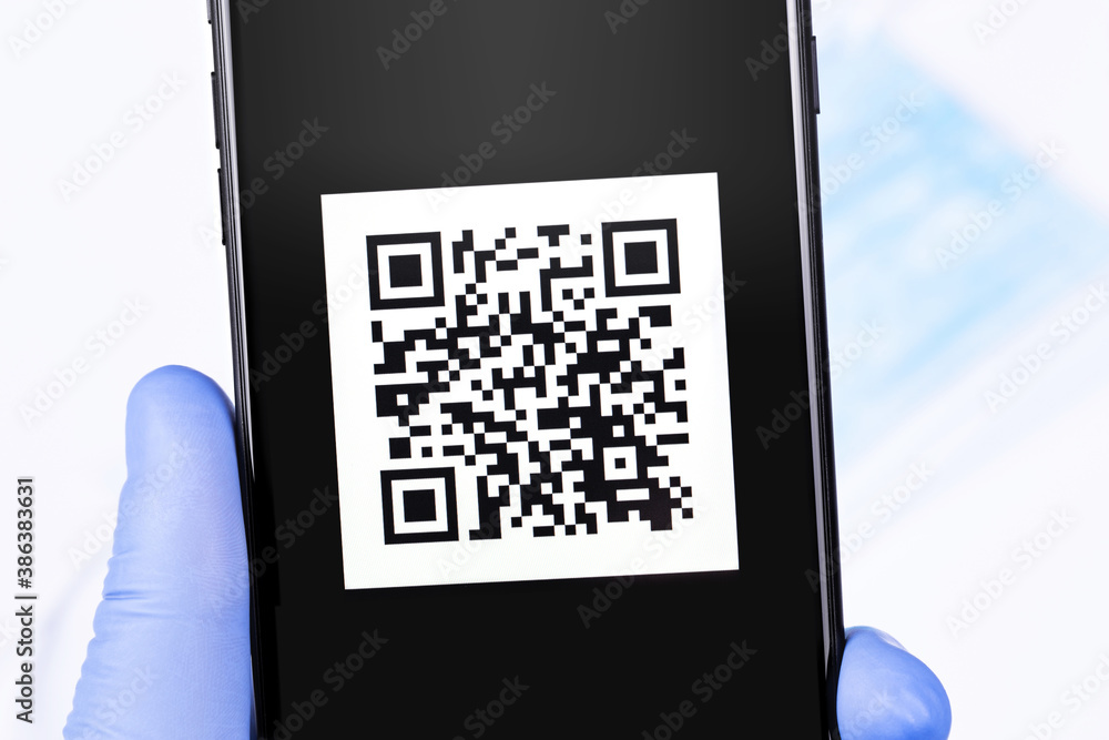 gloved hand holding a smartphone with qr code on the display closeup. COVID-19 (coronavirus ...