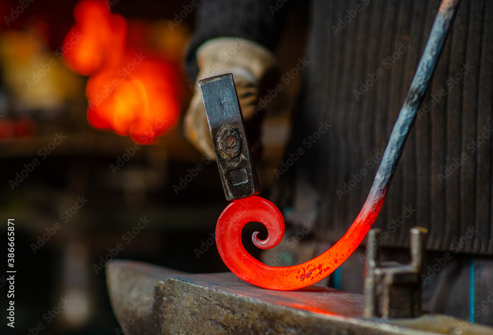 The blacksmith twists the spiral with a sledgehammer, placing a red-hot ...
