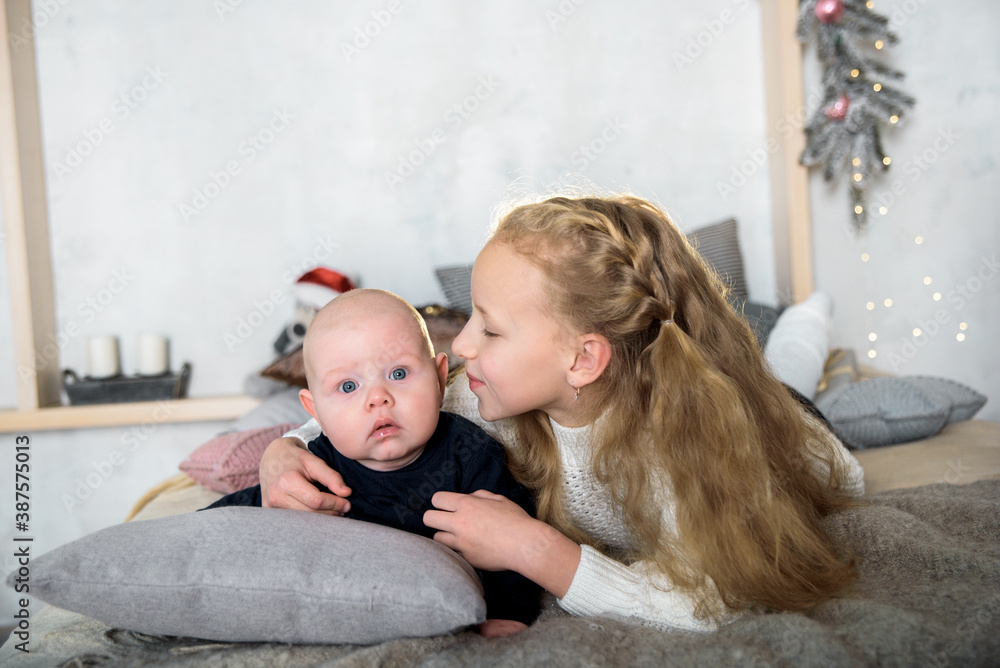 sweet moment between a big sister and her baby brother. The sister is ...