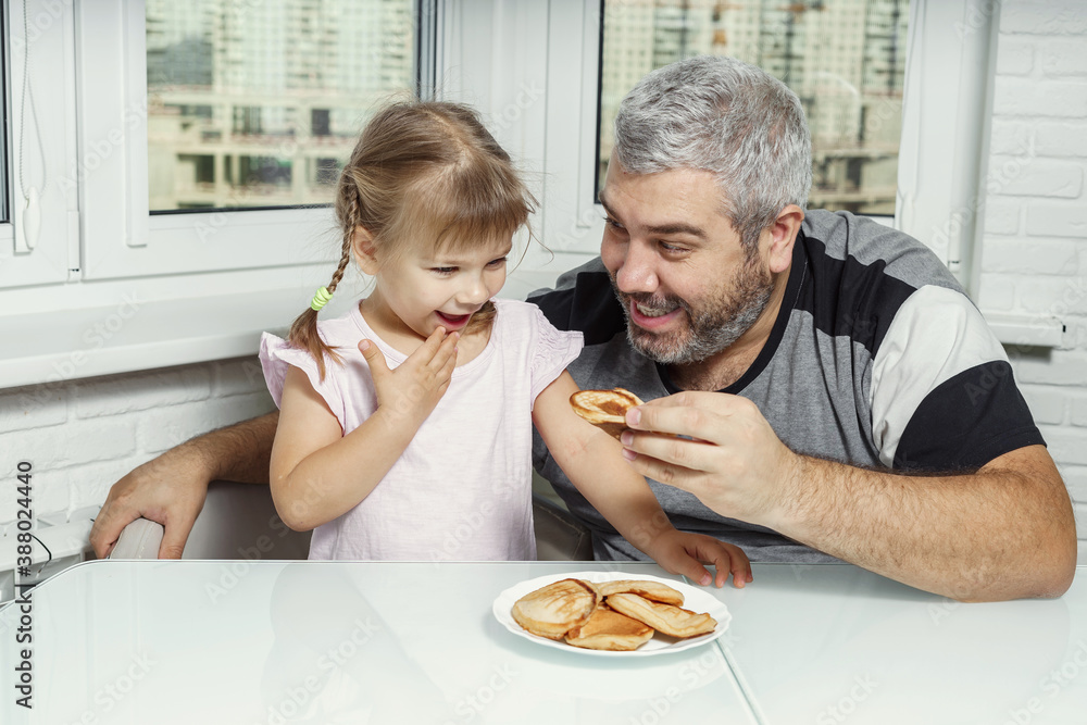 adult gray-haired father at the table with his little daughter. dad ...