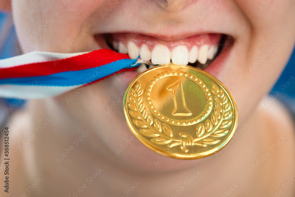Gold medal in teeth. Beautiful young women trying her gold medal by ...