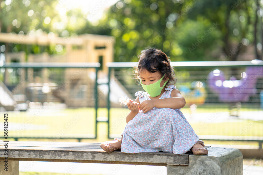girl sitting on park bench wearing healthy face mask to prevent virus ...