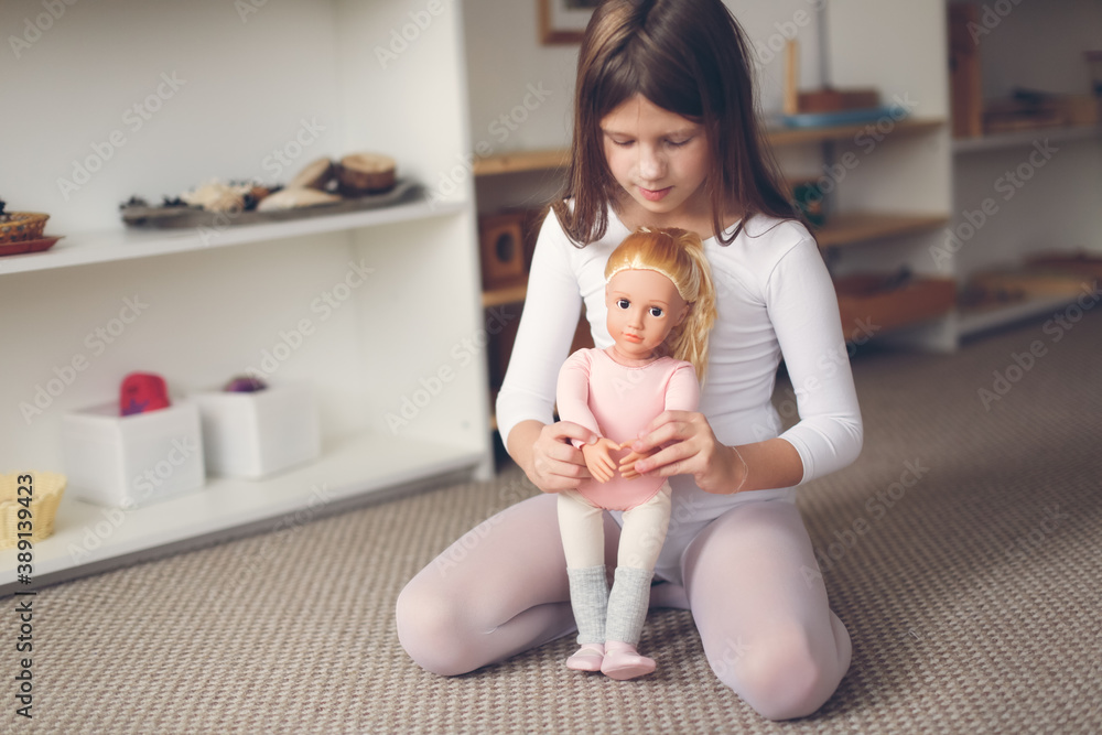 A child girl plays with dolls, a girl in a dance costume is engaged in ...