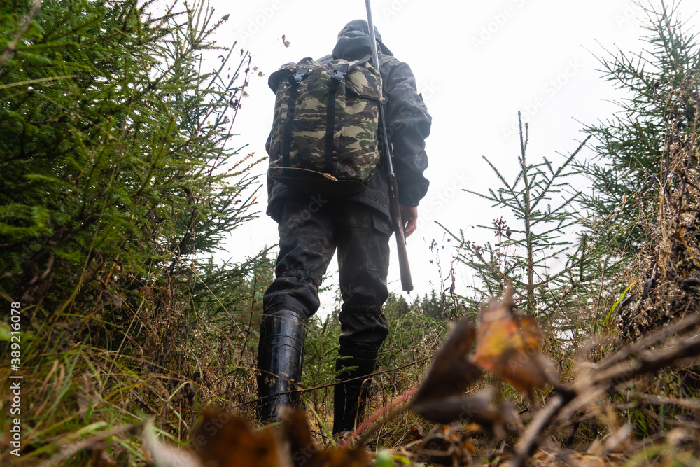 Hunter with a gun and a backpack in the forest Stock Photo | Adobe Stock