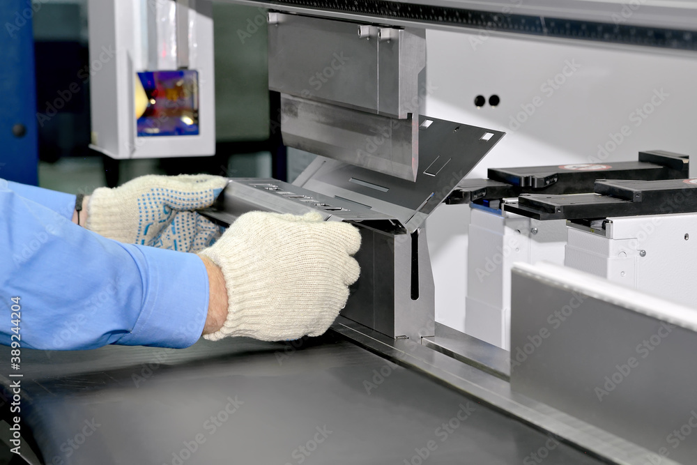 Worker bends a metal plate on the industrial machine. Process of ...