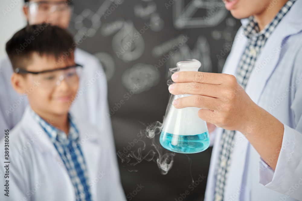 Teacher showing flask with smoking blue liquid to school students when ...
