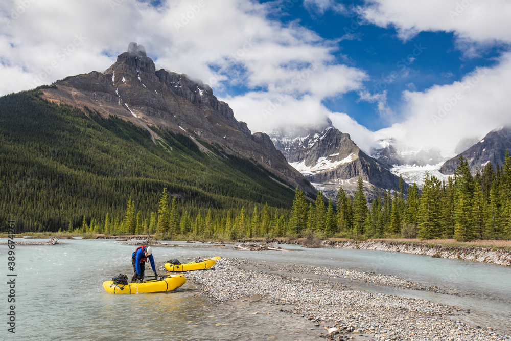Paddler prepares to launch yellow inflatable raft into scenic river ...