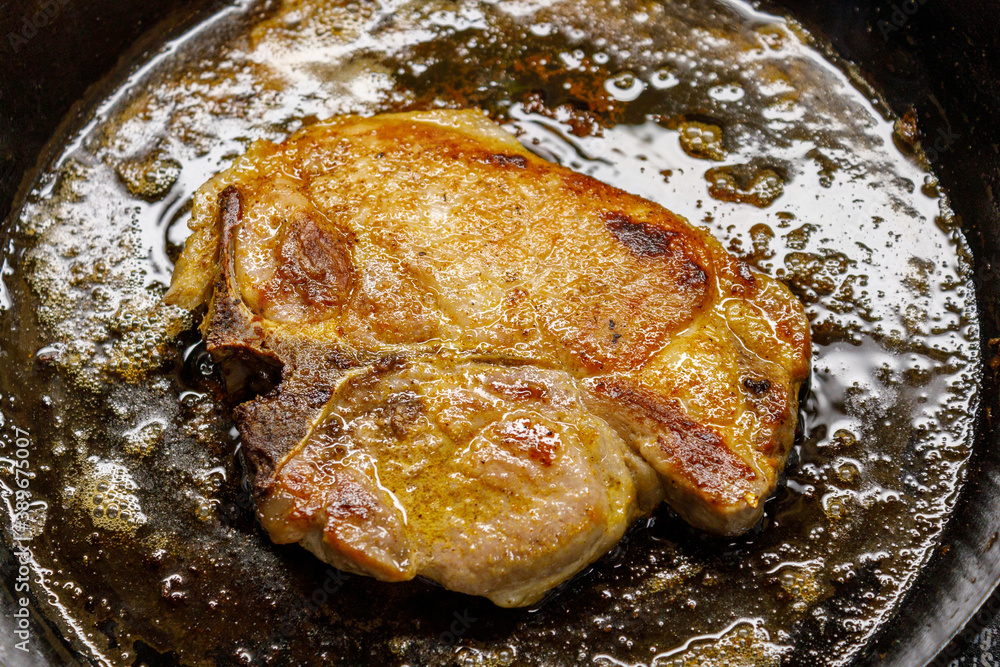 Golden brown pork chop fried in a vintage cast iron skillet の Stock フォト ...