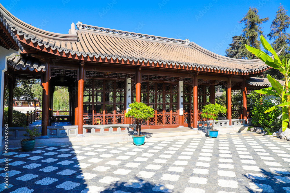 a brown and white Chinese pavilion in a Chinese garden with green ...