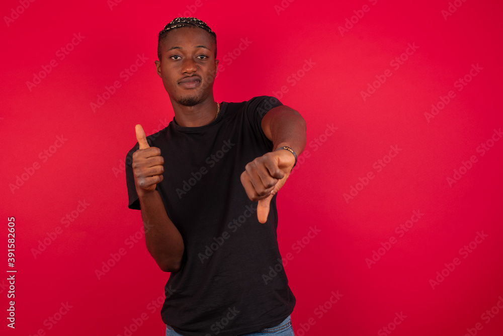 Young African American handsome man standing against red background ...
