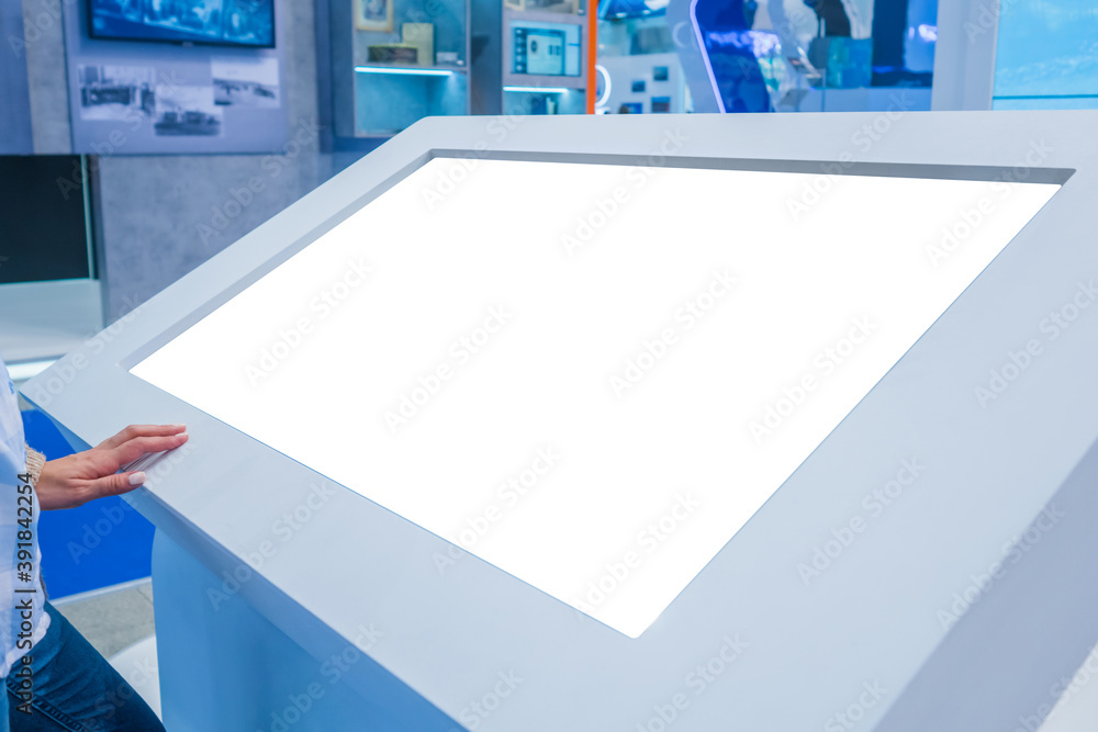Woman looking at blank interactive white display kiosk at exhibition ...