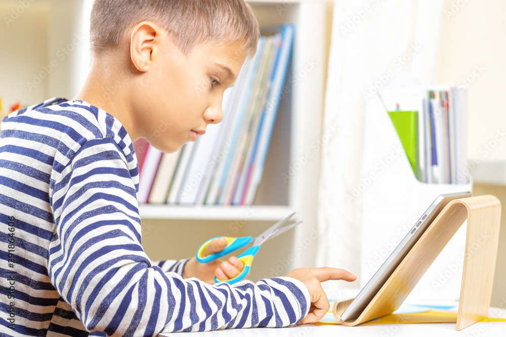 Education, learning, paper craft, entertainment. Teenage boy cutting ...