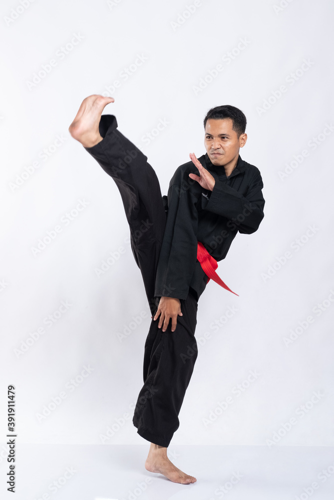 man in pencak silat uniform poses forward kick movement on isolated ...