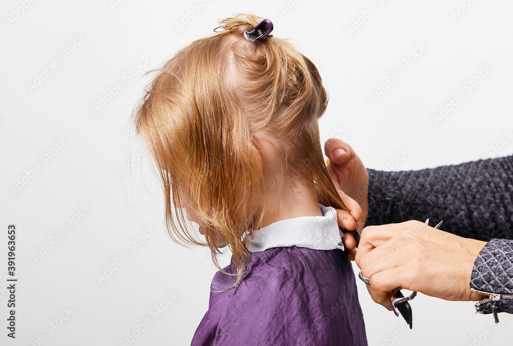 Hair cutting process. Beautiful little girl at the barber shop ...
