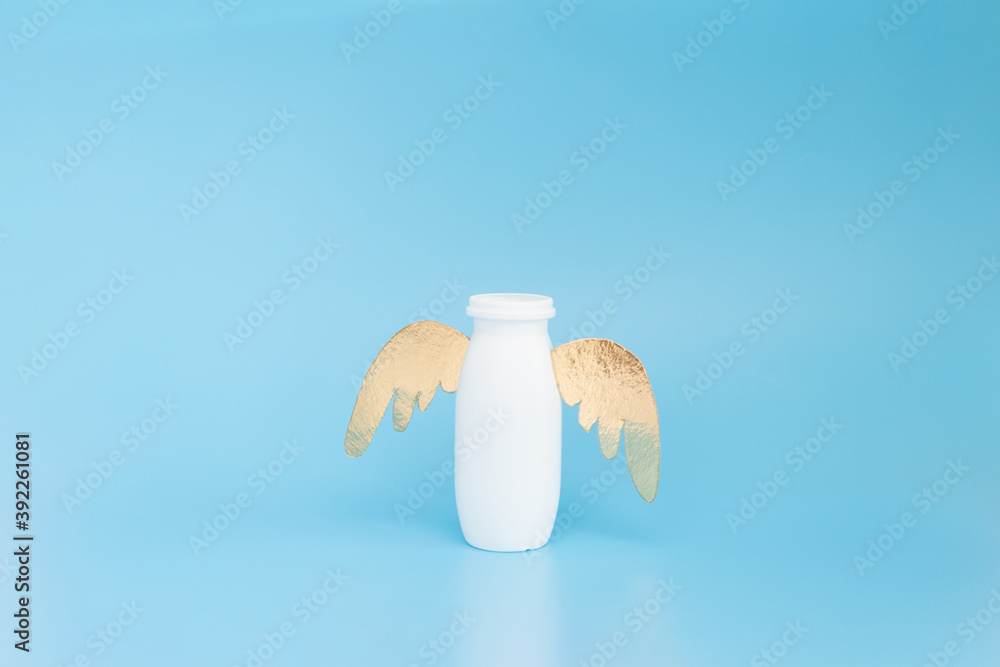 empty yogurt white plastic bottle with golden wings glue on it, blue ...