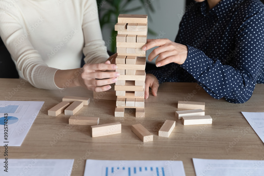 Close up diverse colleagues building tower from wooden blocks in office ...