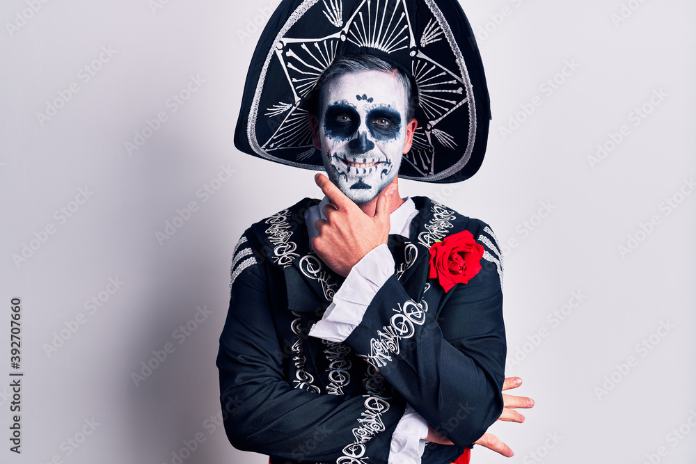 Young man wearing mexican day of the dead costume over white looking ...