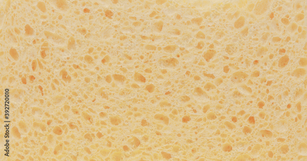 The pale yellow surface of a sponge, with many holes, also looking like ...