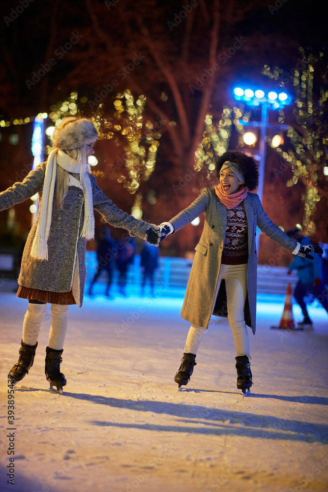 Female friends skating together at ice rink. Skating, friendship ...