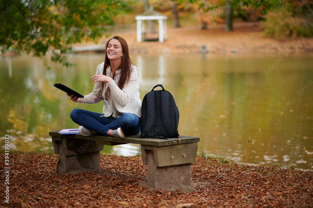 Beautiful young college student sits alone on campus in fall leaves ...