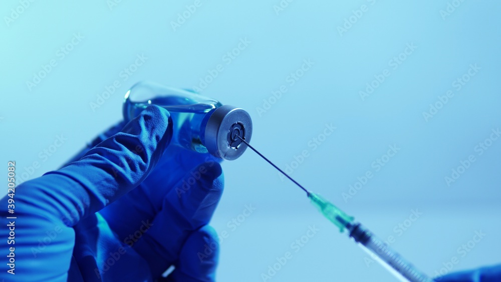 Filling syringe with vaccine from vial, close up. Administrating ...