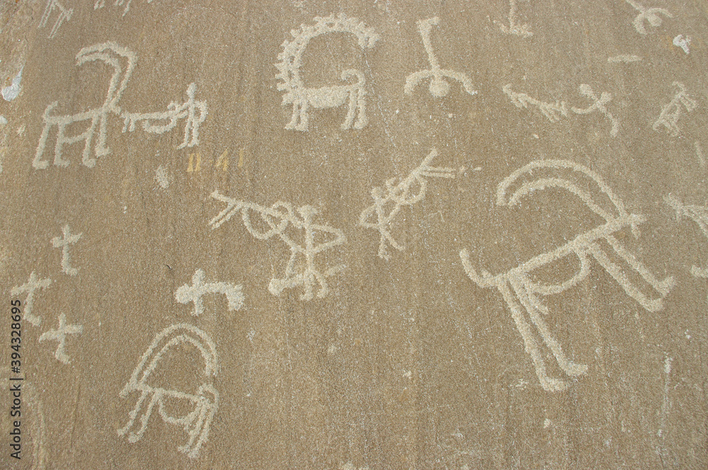 Ibex and men with guns carving on rock: detail of ancient silk road era petroglyphs above Langar ...