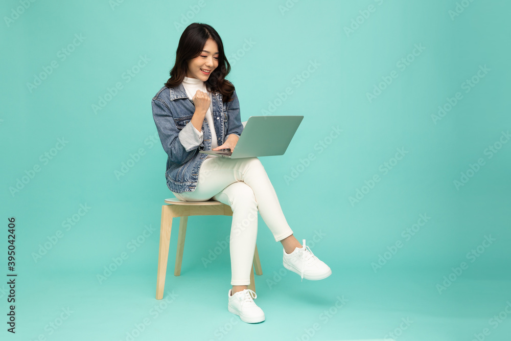 Young happy smiling Asian woman holding laptop computer and sitting on ...