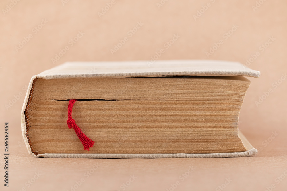 Thick book with red rope bookmark lying on brown paper background ...